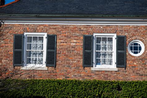 맑고 푸른 하늘을 배경으로 셔터와 둥근 창문이 특징인 유서 깊은 벽돌집 외관은 매력적인 동네에서 고전적인 건축 양식을 보여줍니다 건물 외관에 대한 스톡 사진 및 기타 이미지
