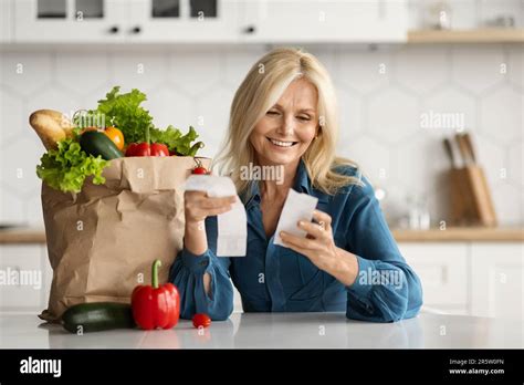 Market Delivery Happy Mature Woman Checking Bills In Kitchen After