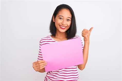 확인 기호를하고 큰 미소 손가락 우수한 기호와 엄지 손가락으로 행복 고립 된 흰색 배경 위에 서 배너를 들고 젊은 아름다운 중국