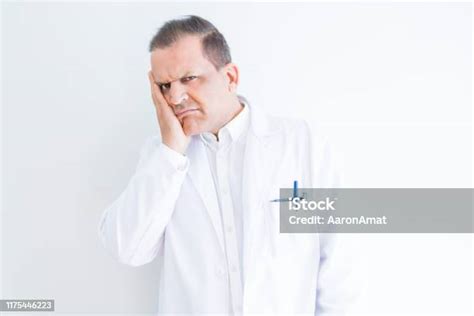 흰색 배경에 의료 코트를 입고 중년 의사 남자 피곤 하 고 교차 된 팔을 가진 우울증 문제로 지루 해 보이는 생각 건강관리와