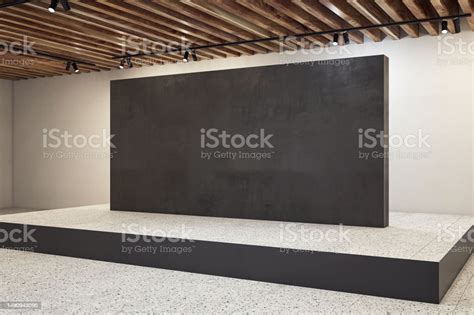 넓은 현대 전시장에서 큰 연단과 베이지색 벽 배경에 있는 콘크리트 바닥에 있는 검은색 빈 벽의 측면 모습 프리젠테이션 및 쇼룸 개념 3d 렌더링 모형 0명에 대한 스톡 사진