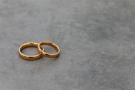 Te casarías conmigo dos anillos de boda dorados sobre fondo gris de