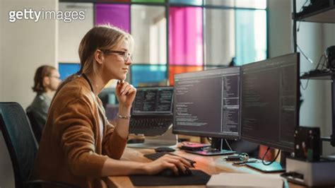 Female Software Engineer Writing Code On Desktop Computer With Multiple
