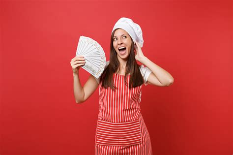 스트라이프 앞치마 흰색 티셔츠 모자 요리사 모자 빨간 벽 배경에 고립에서 주부 여성 요리사 요리사 베이커 행복 한 여자 들고